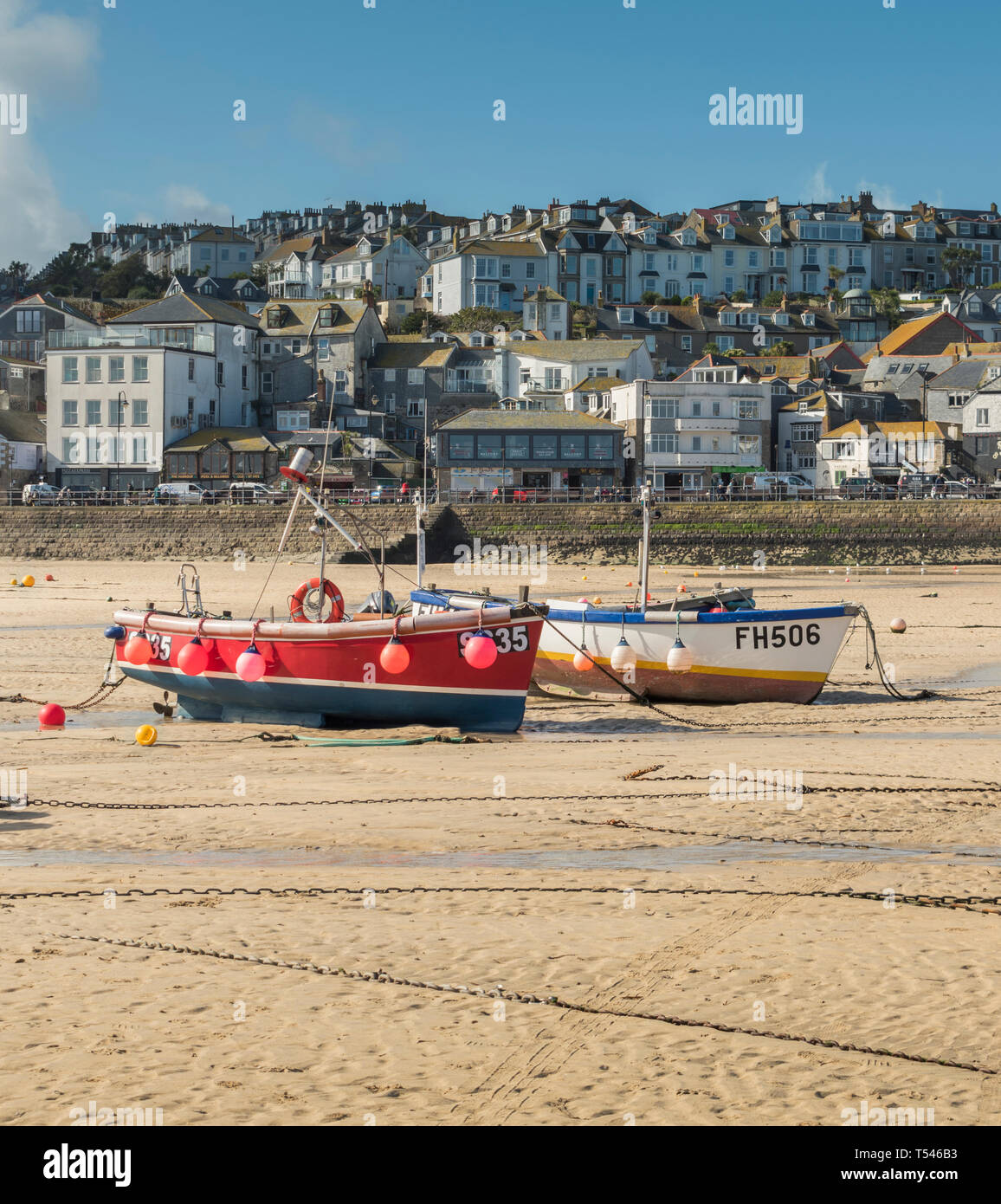 Colourful fishing boats stranded by the low tide in St Ives Harbour ...