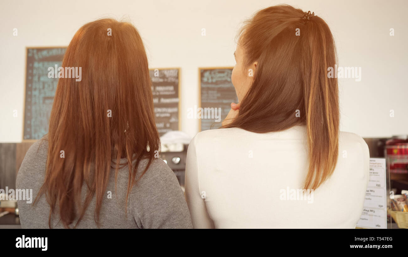 Two women discuss the menu and choose food in a cafe standing at the ...
