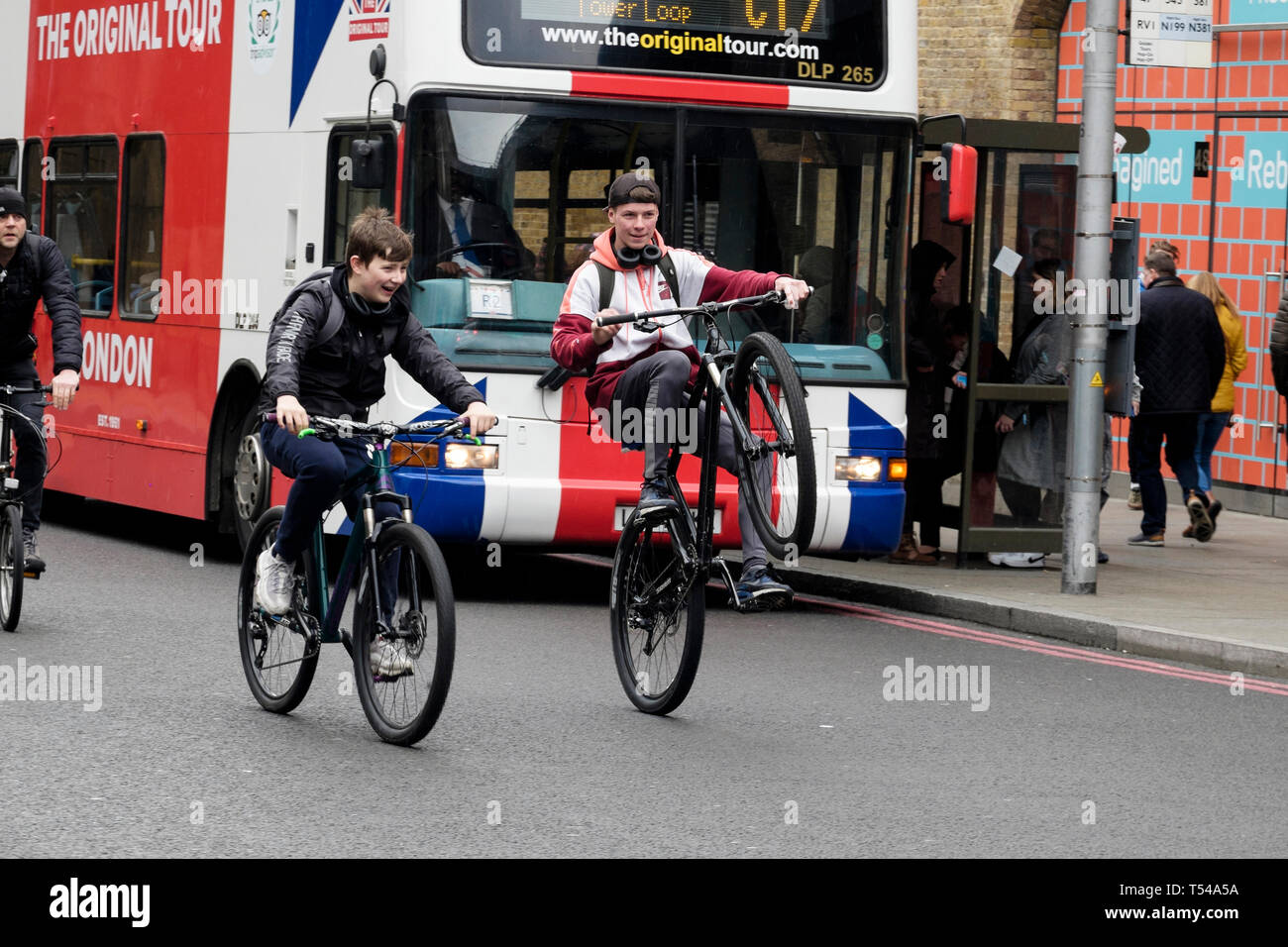 Two teenage boys on bikes, one performing a wheelie stunt. London, UK ...