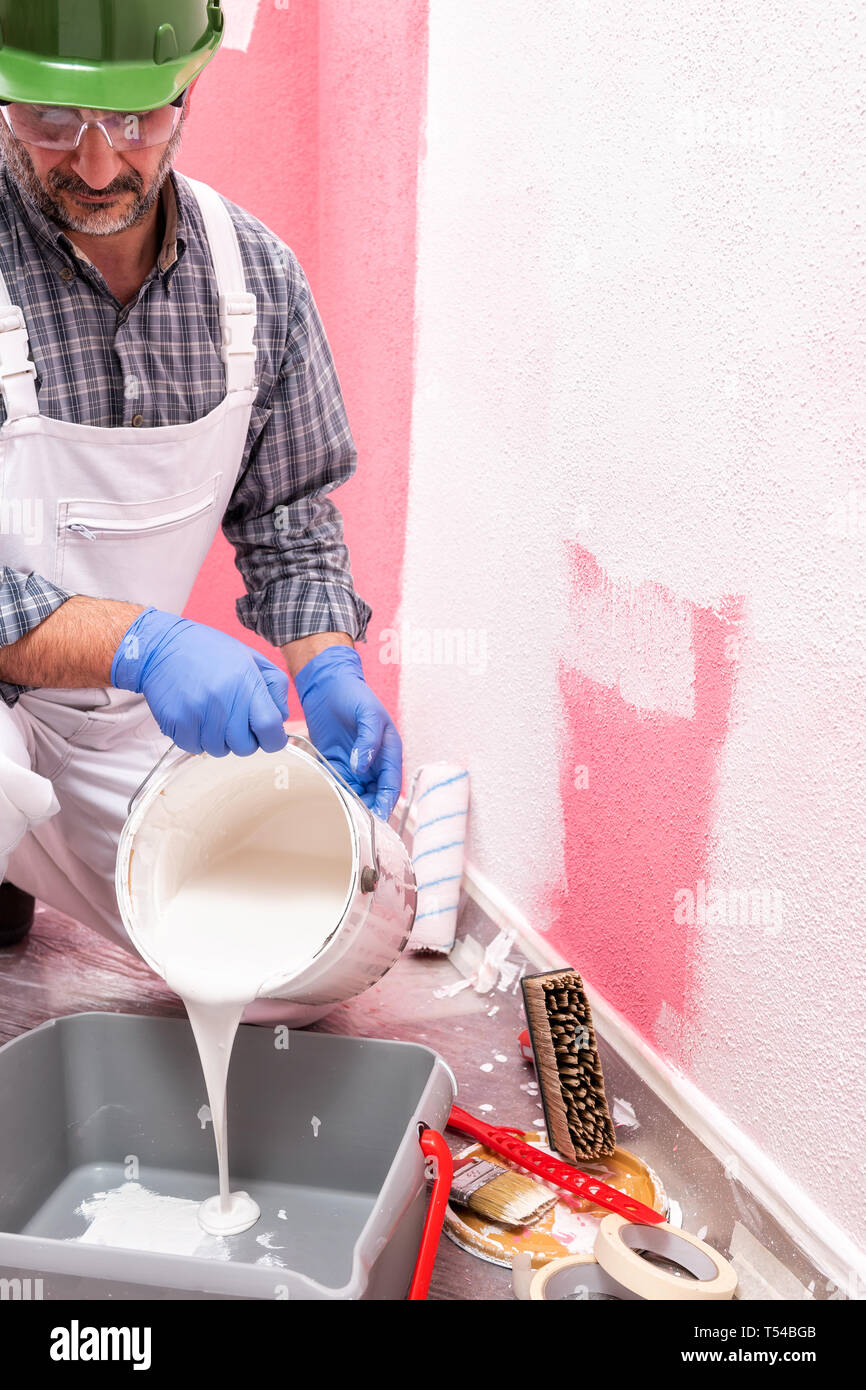 Caucasian house painter worker in white overalls, with helmet and ...