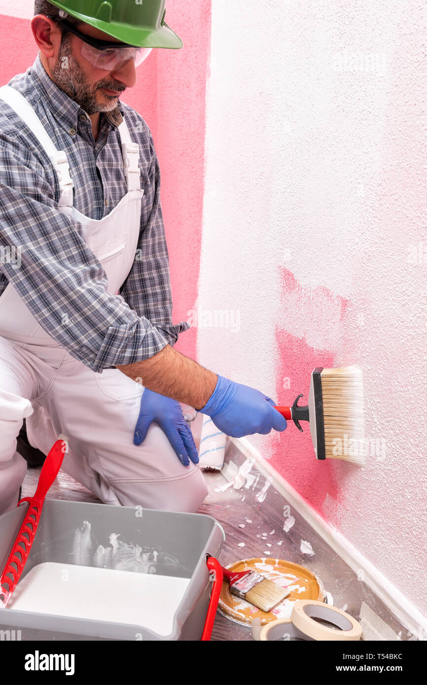 Caucasian house painter worker in white overalls, with helmet and ...