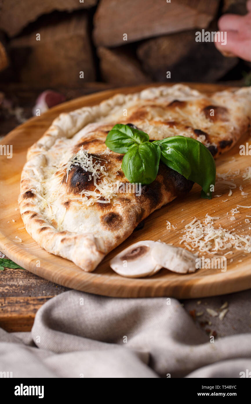 Pizza Calzone folded in half is decorated with basil on the background ...