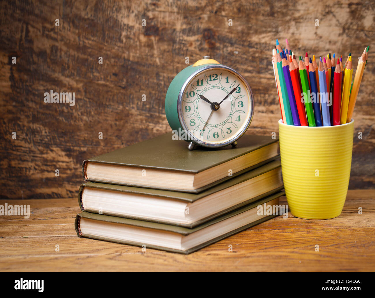 An old clock on the books on the table at the student. Education ...