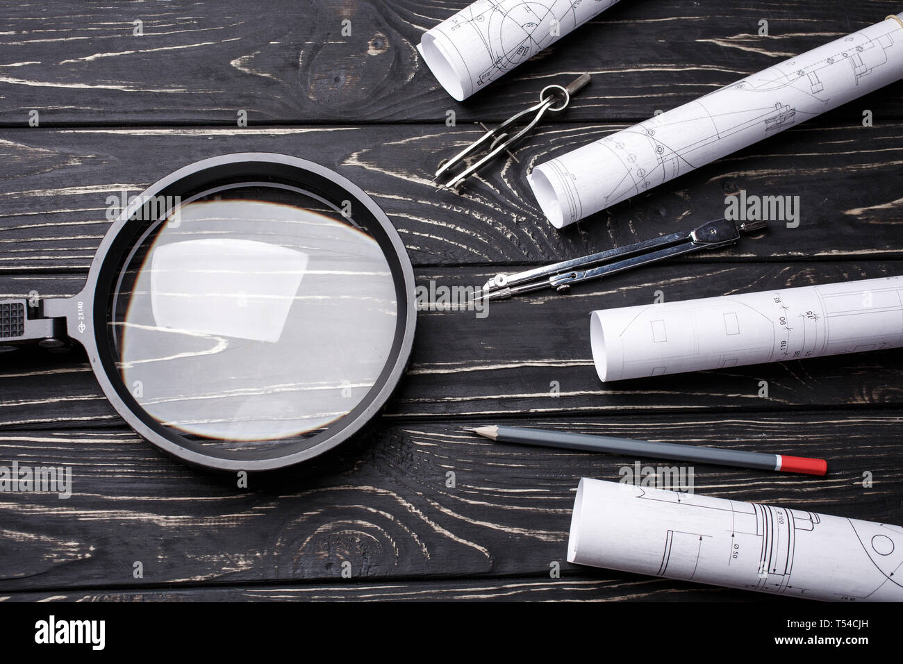 Magnifying glass with drawing tools and rolls drawings on a black ...