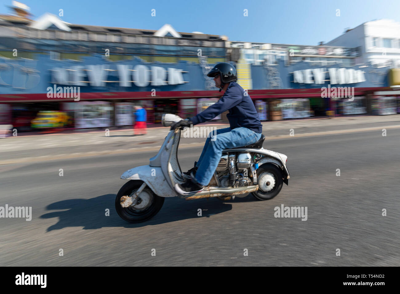 Motor scooter rider riding along the seafront at Marine Parade ...