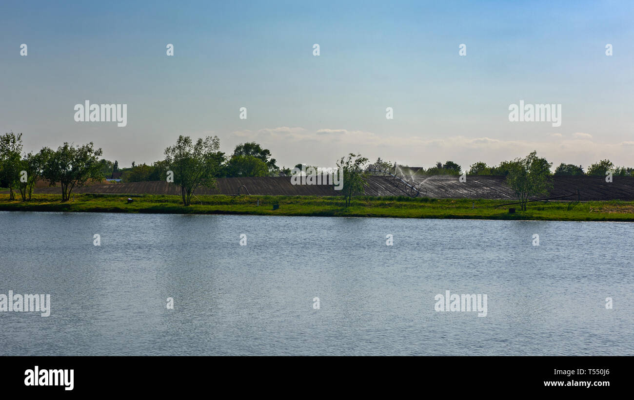 Picture of the lake at dusk and watering the field above the lake with ...