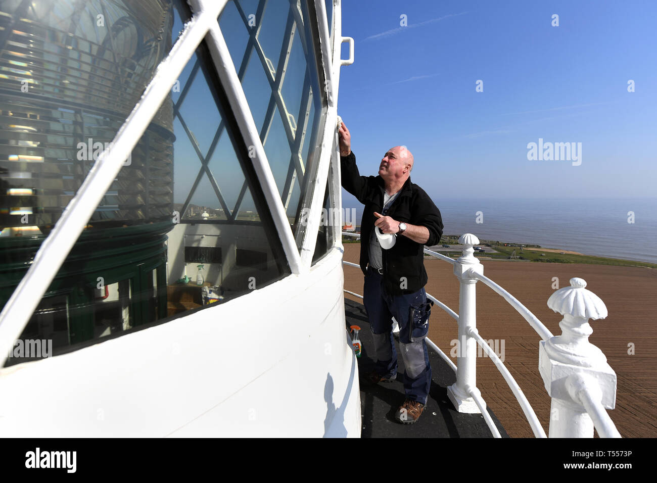 Lighthouse attendant Chris Moore cleans the glass on the outside of the ...