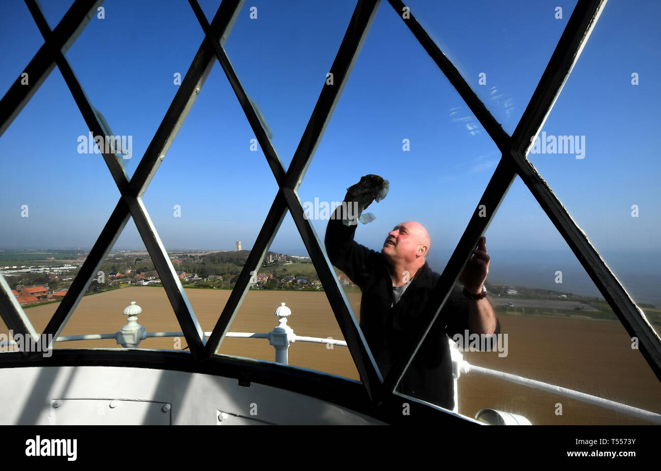 Lighthouse attendant Chris Moore cleans the glass on the outside of the ...