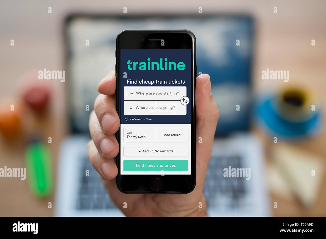 A man looks at his iPhone which displays the Trainline logo (Editorial ...