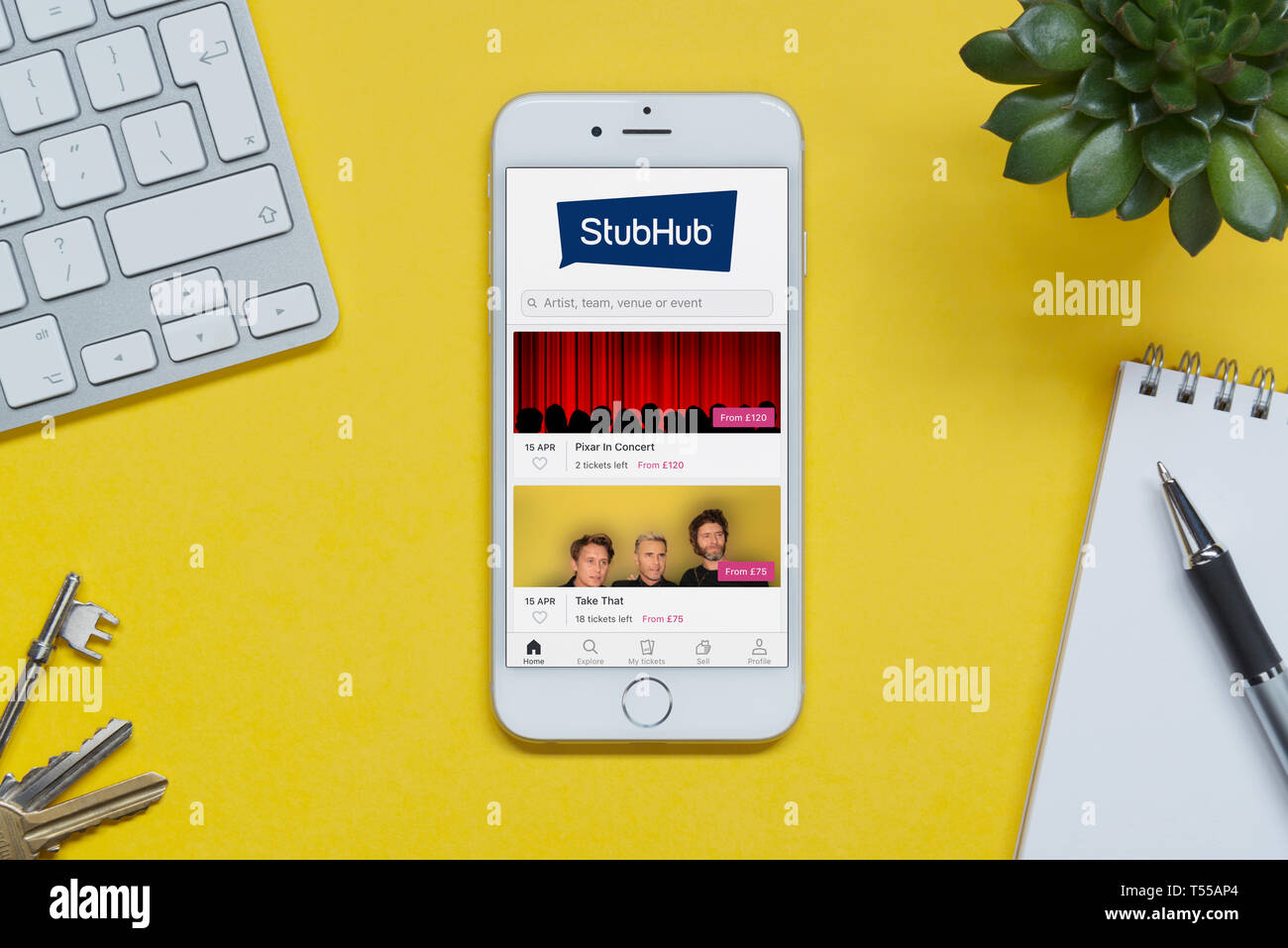 An iPhone showing the StubHub website rests on a yellow background ...
