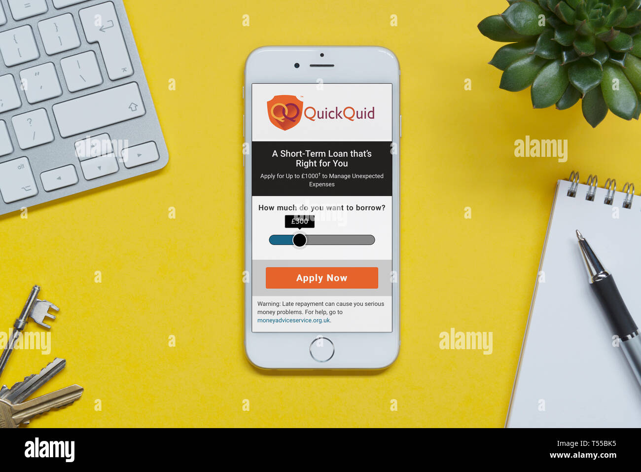 An iPhone showing the Quick Quid website rests on a yellow background ...