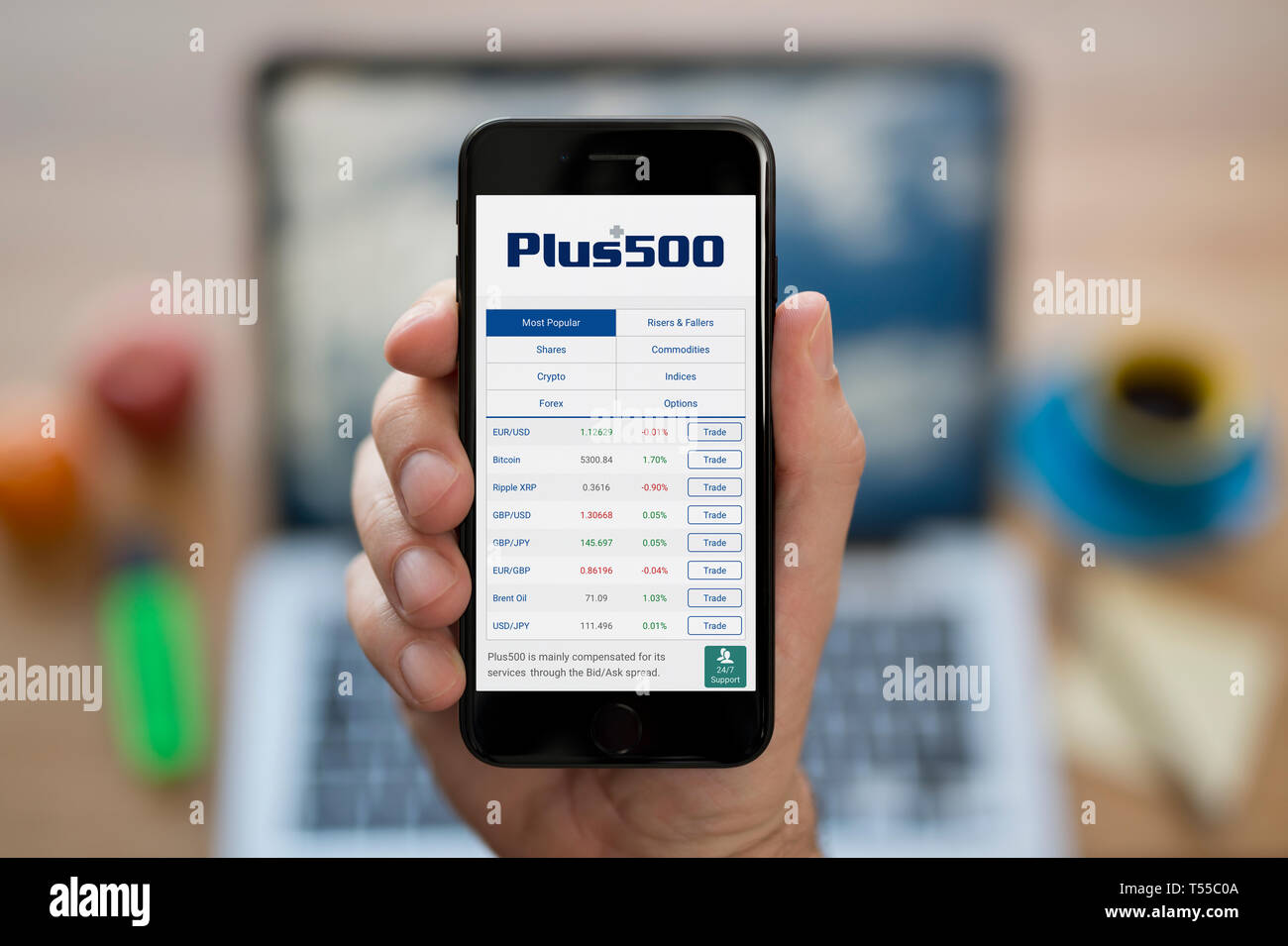 A man looks at his iPhone which displays the Plus 500 logo (Editorial ...