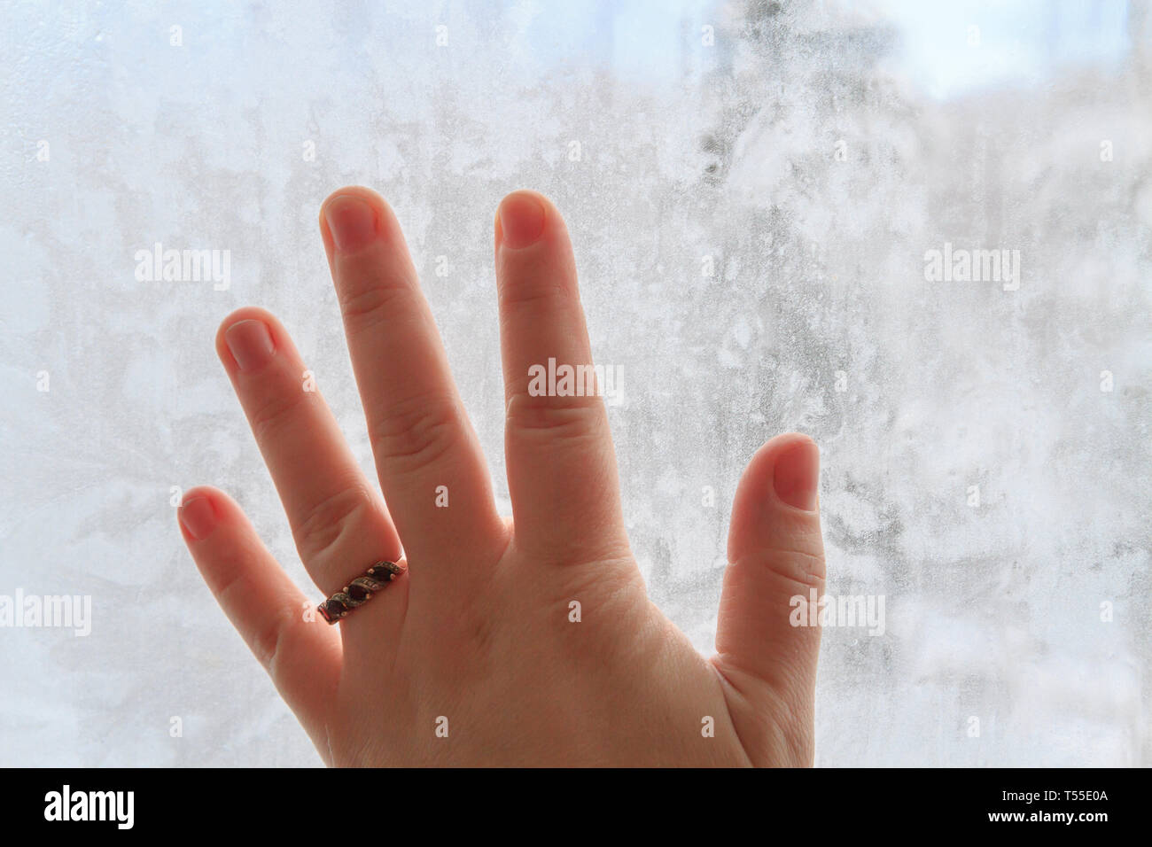 Hand on frozen winter cold window with patterns Stock Photo - Alamy