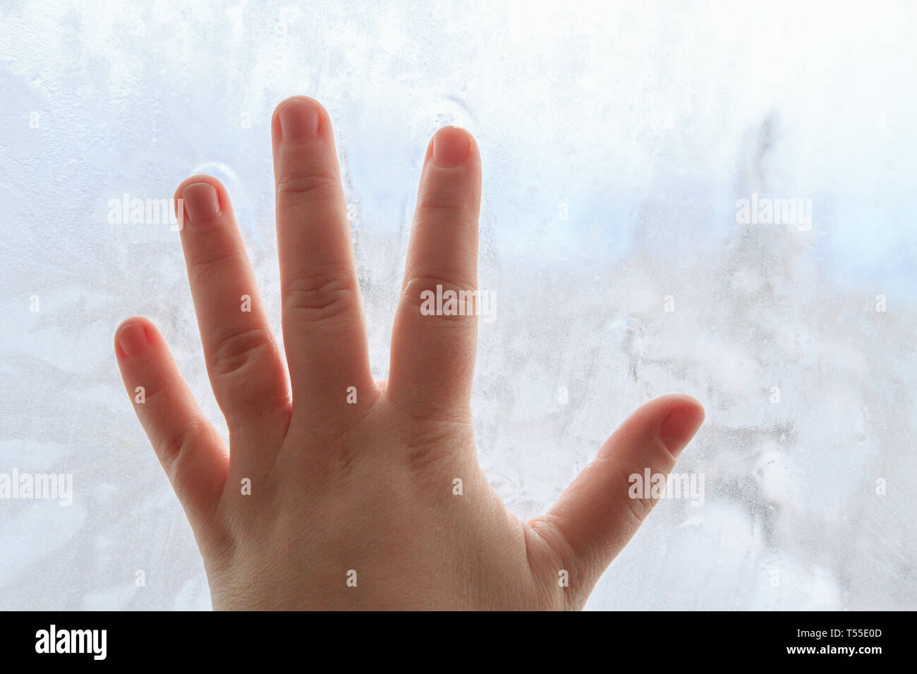 Hand on frozen winter cold window with patterns Stock Photo - Alamy