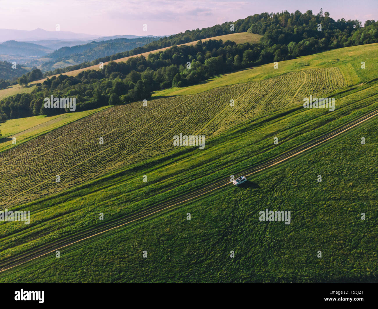 white suv car in mountains at path trail on sunset. aerial view Stock ...