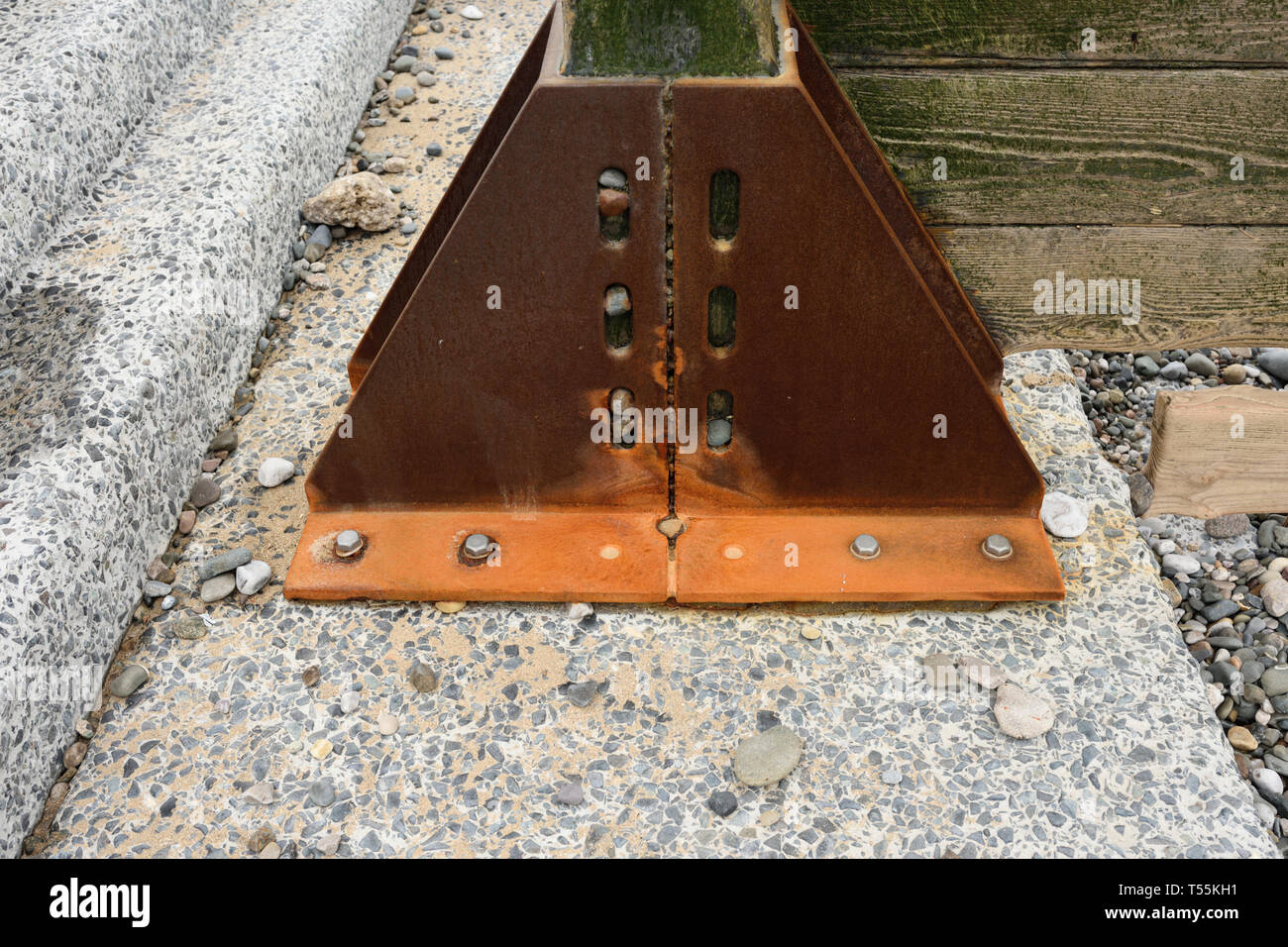 Rusty steel mounting attached to wooden beach groyne, fixed to concrete ...
