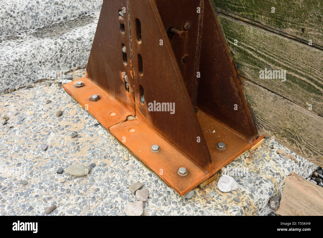 Rusty steel mounting attached to wooden beach groyne, fixed to concrete ...