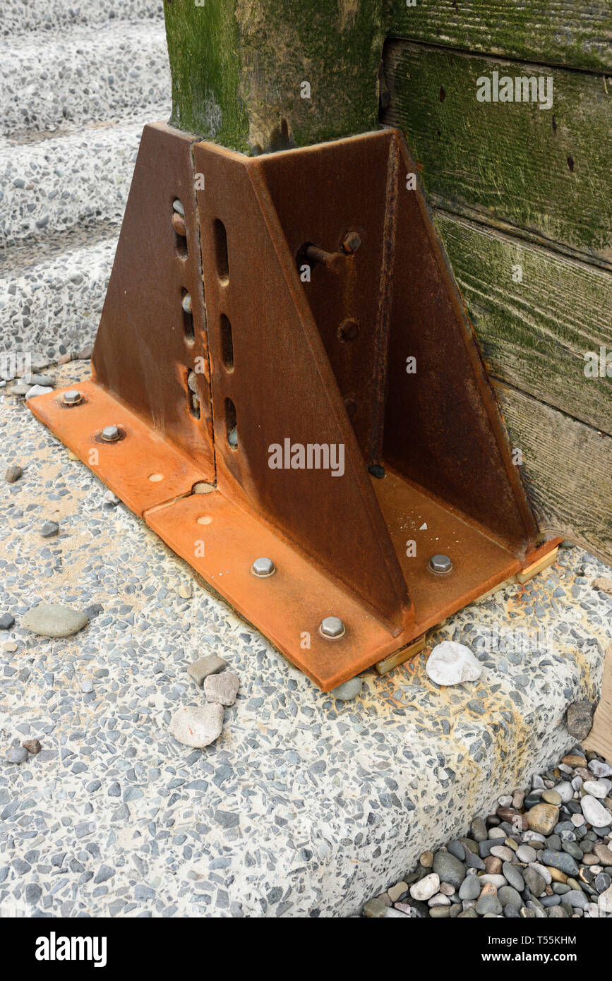 Rusty steel mounting attached to wooden beach groyne, fixed to concrete ...