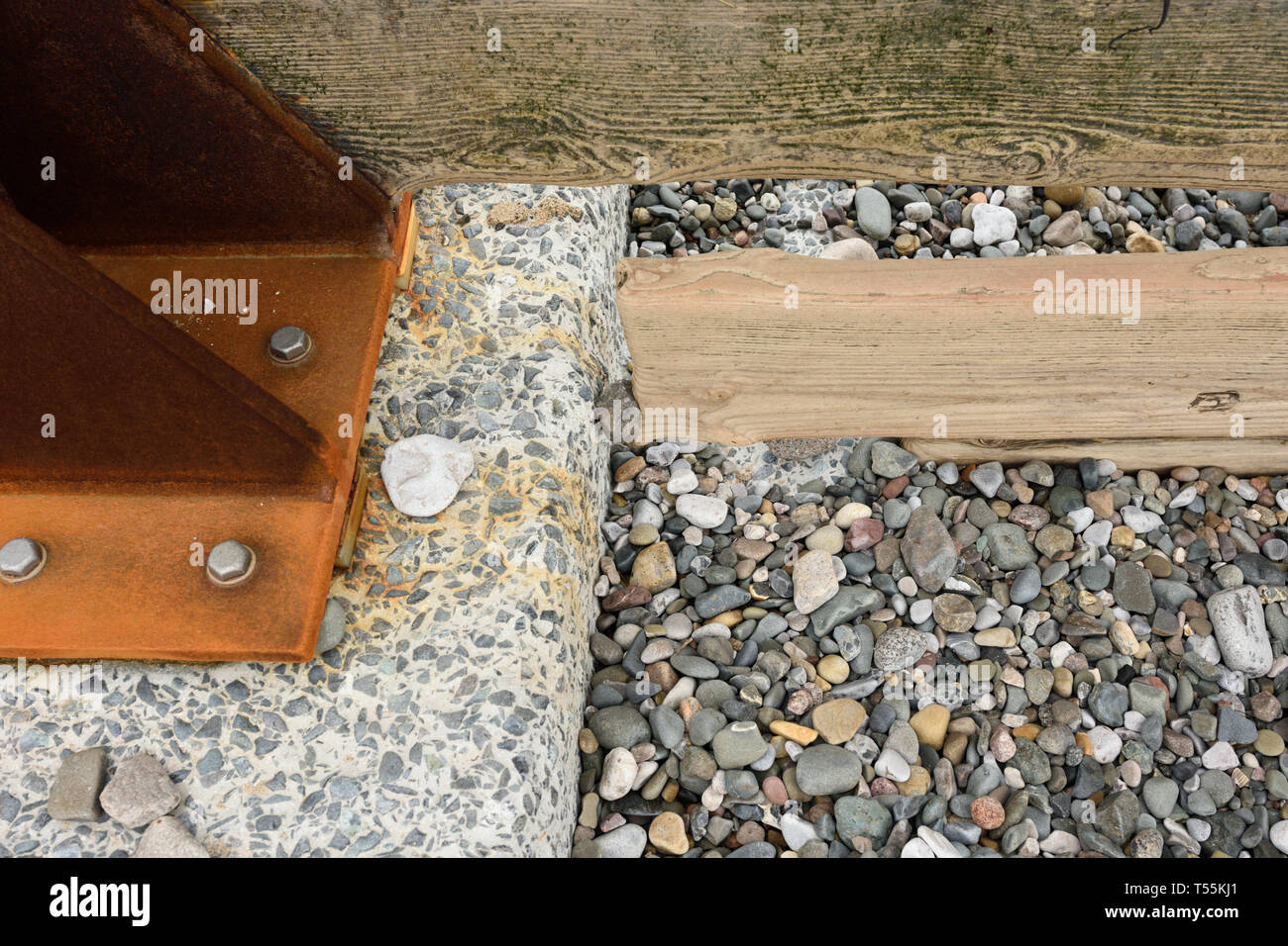 Rusty steel mounting attached to wooden beach groyne, fixed to concrete ...