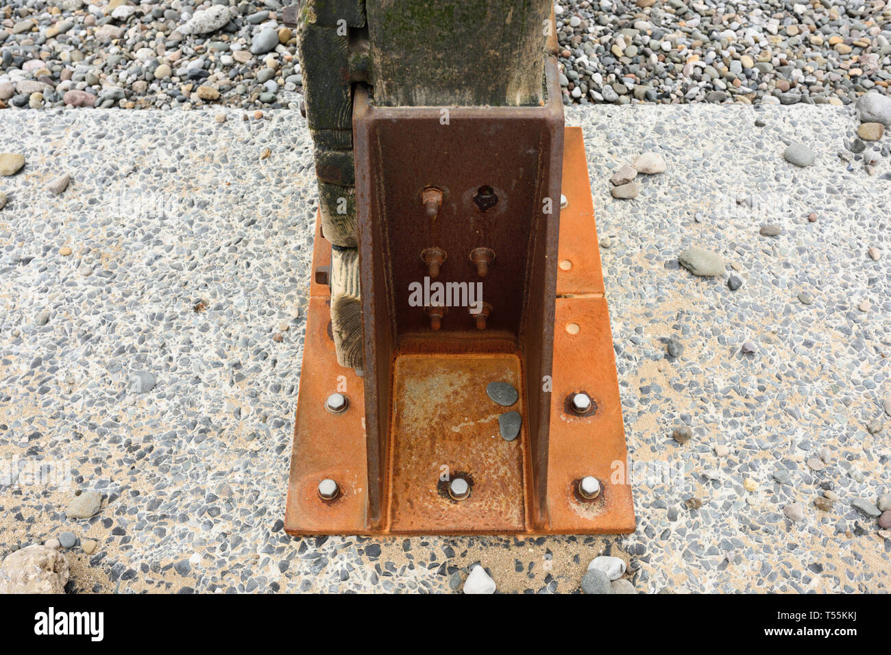 Rusty steel mounting attached to wooden beach groyne, fixed to concrete ...
