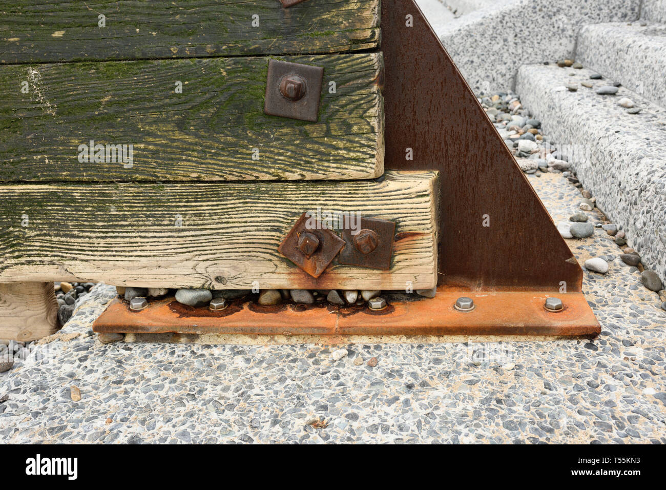 Rusty steel mounting attached to wooden beach groyne, fixed to concrete ...