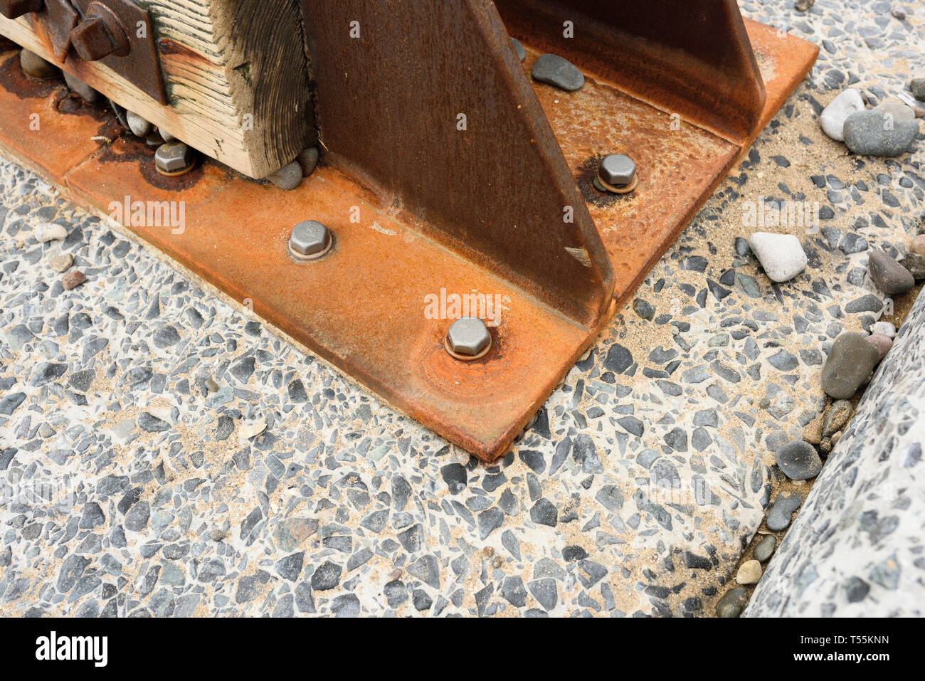 Rusty steel mounting attached to wooden beach groyne, fixed to concrete ...