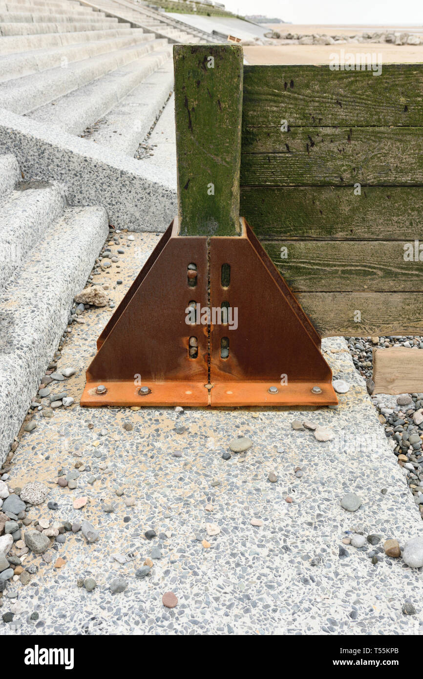 Rusty steel mounting attached to wooden beach groyne, fixed to concrete ...