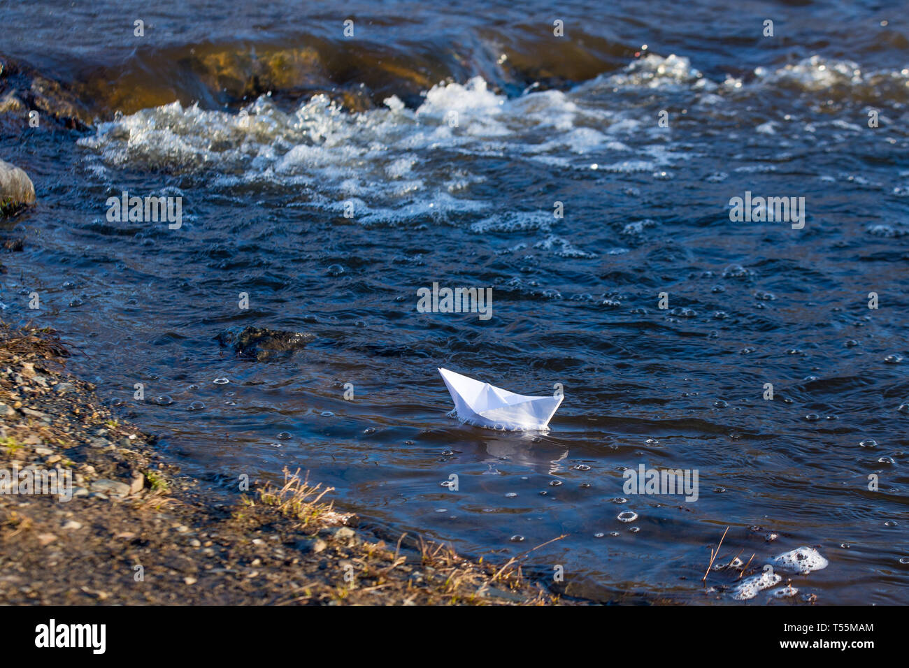 A paper boat on a turbulent stream of water struggles with the flow ...