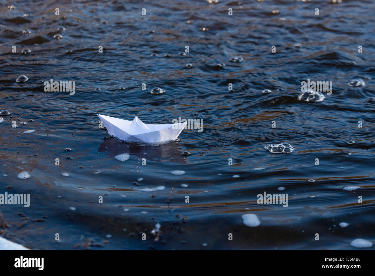 A paper boat on a turbulent stream of water struggles with the flow ...