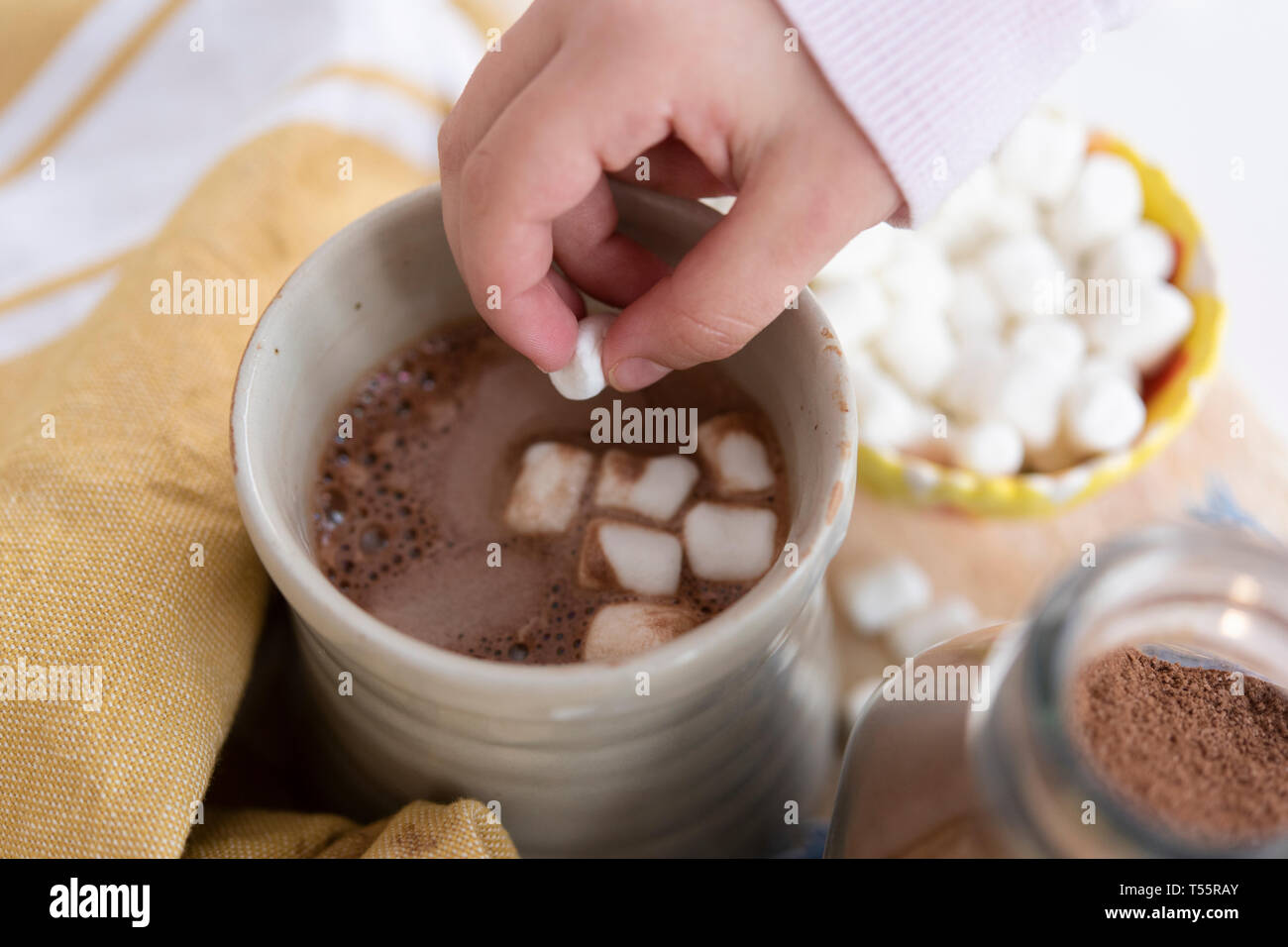 Girl's hand putting marshmallows in hot chocolate Stock Photo - Alamy