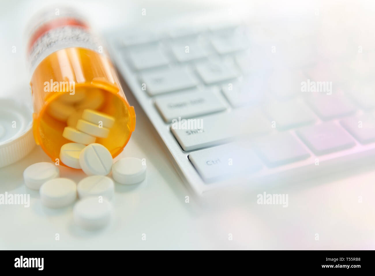 Spilled pill bottle by computer keyboard Stock Photo - Alamy