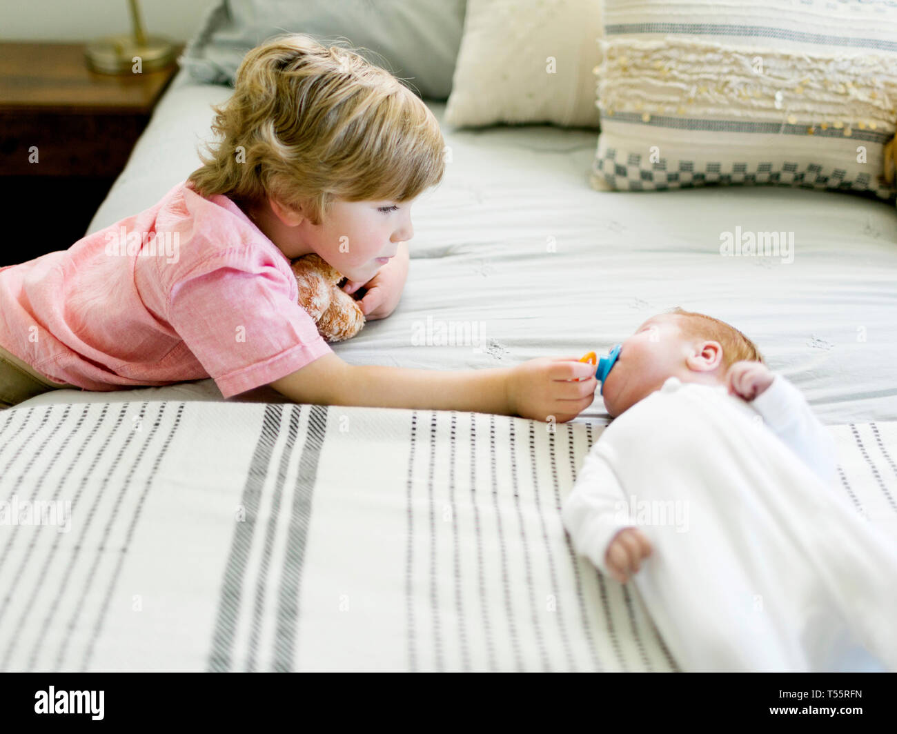 Boy holding his baby brothers pacifier Stock Photo - Alamy
