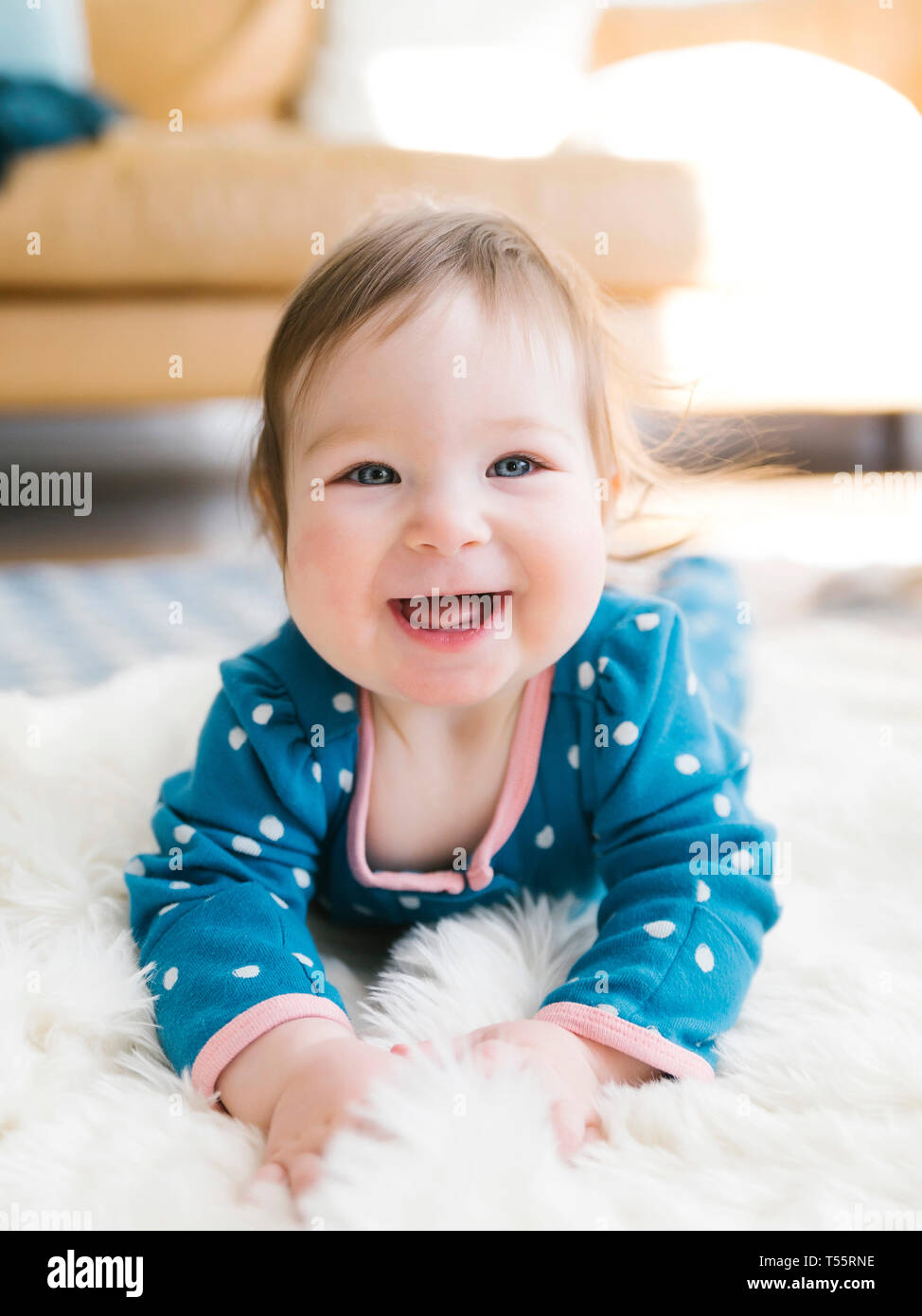 Smiling baby girl lying on rug Stock Photo - Alamy