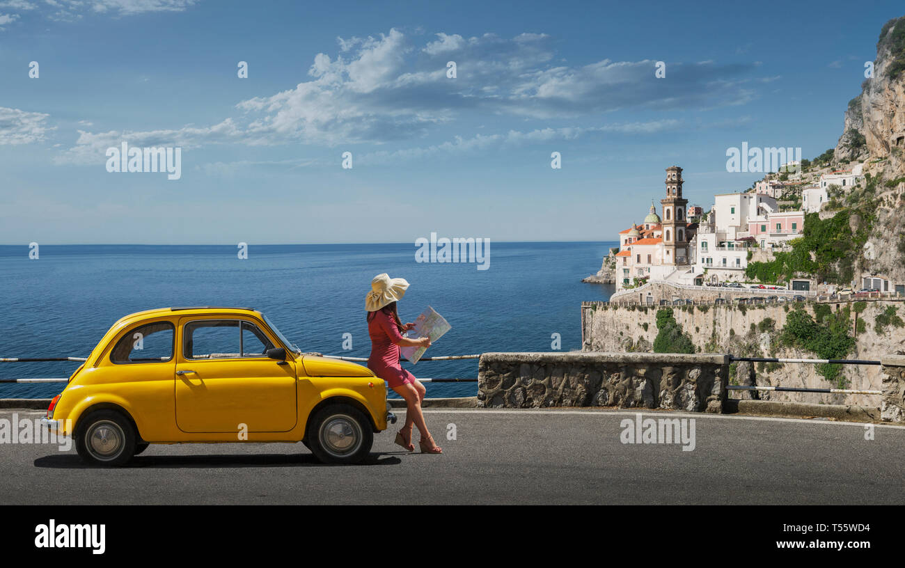 Woman holding map leaning on yellow car in Atrani, Italy Stock Photo ...