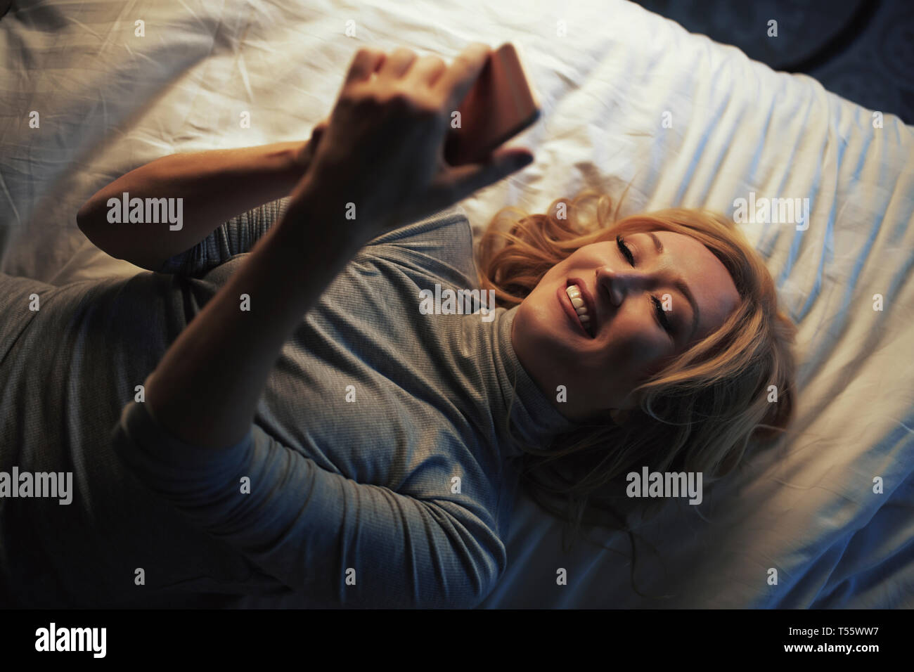 Woman using smart phone while lying on bed Stock Photo - Alamy