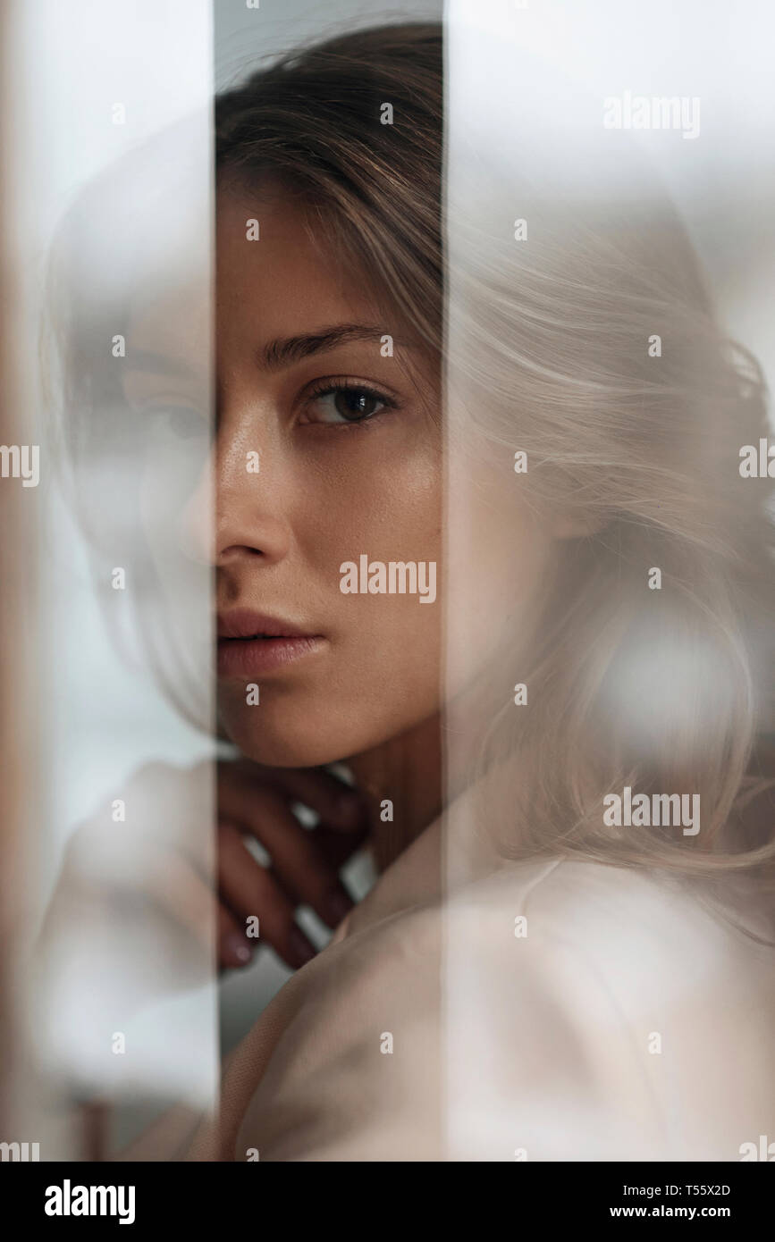 Portrait of young woman behind window Stock Photo - Alamy