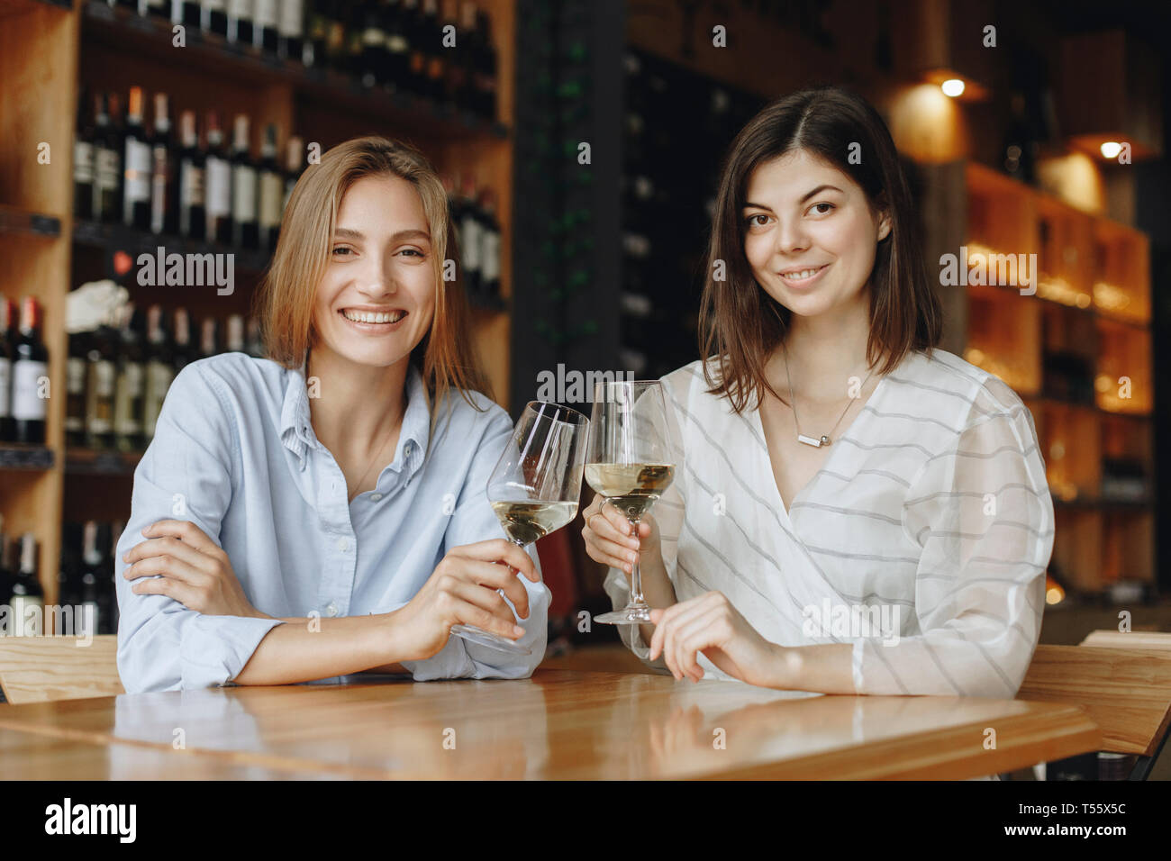 Young women toasting with glasses of white wine Stock Photo - Alamy