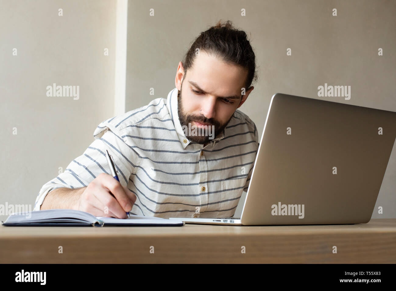 Young businessman with laptop writing in note pad Stock Photo - Alamy