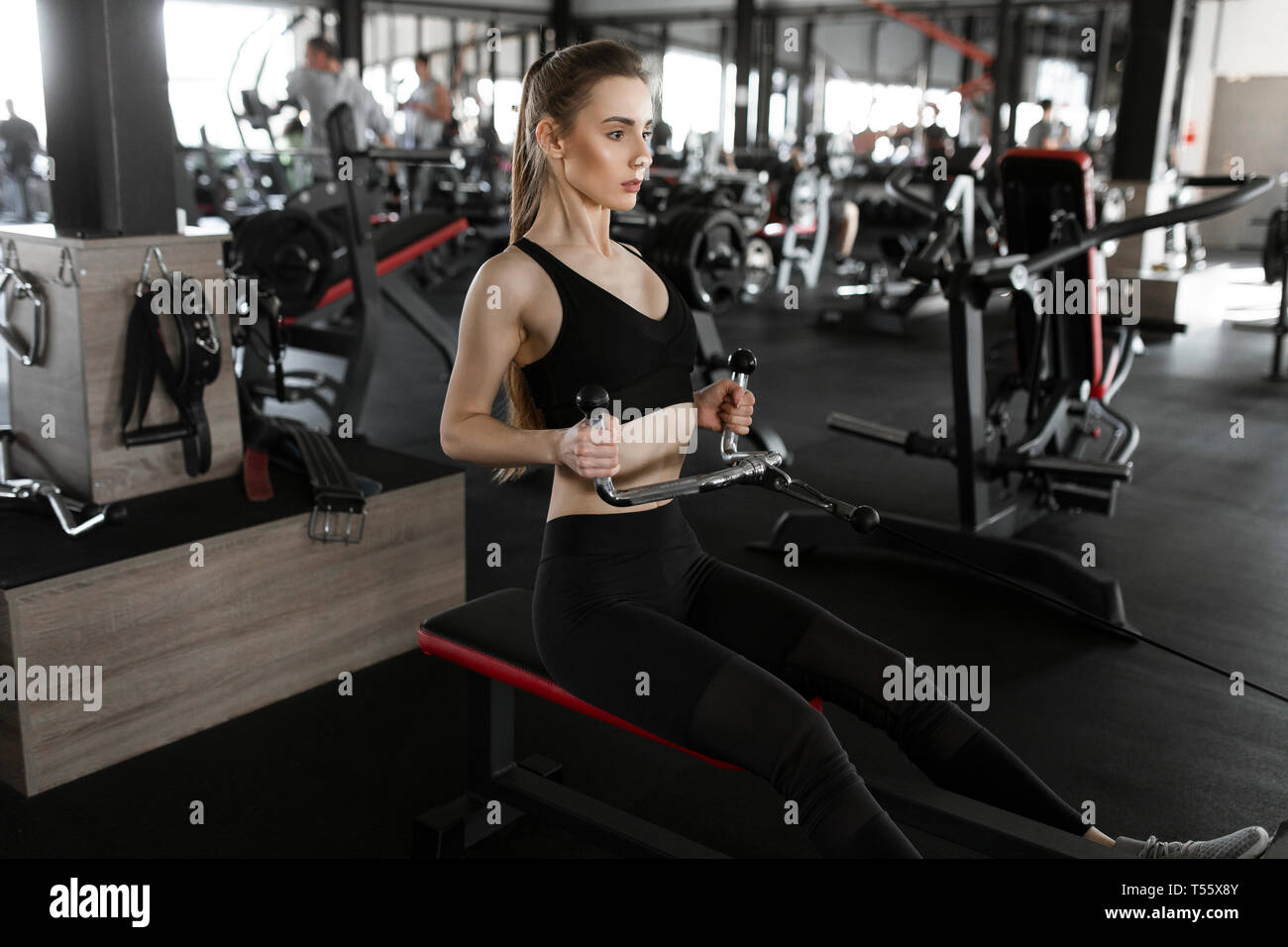 Young woman using exercise machine in gym Stock Photo - Alamy