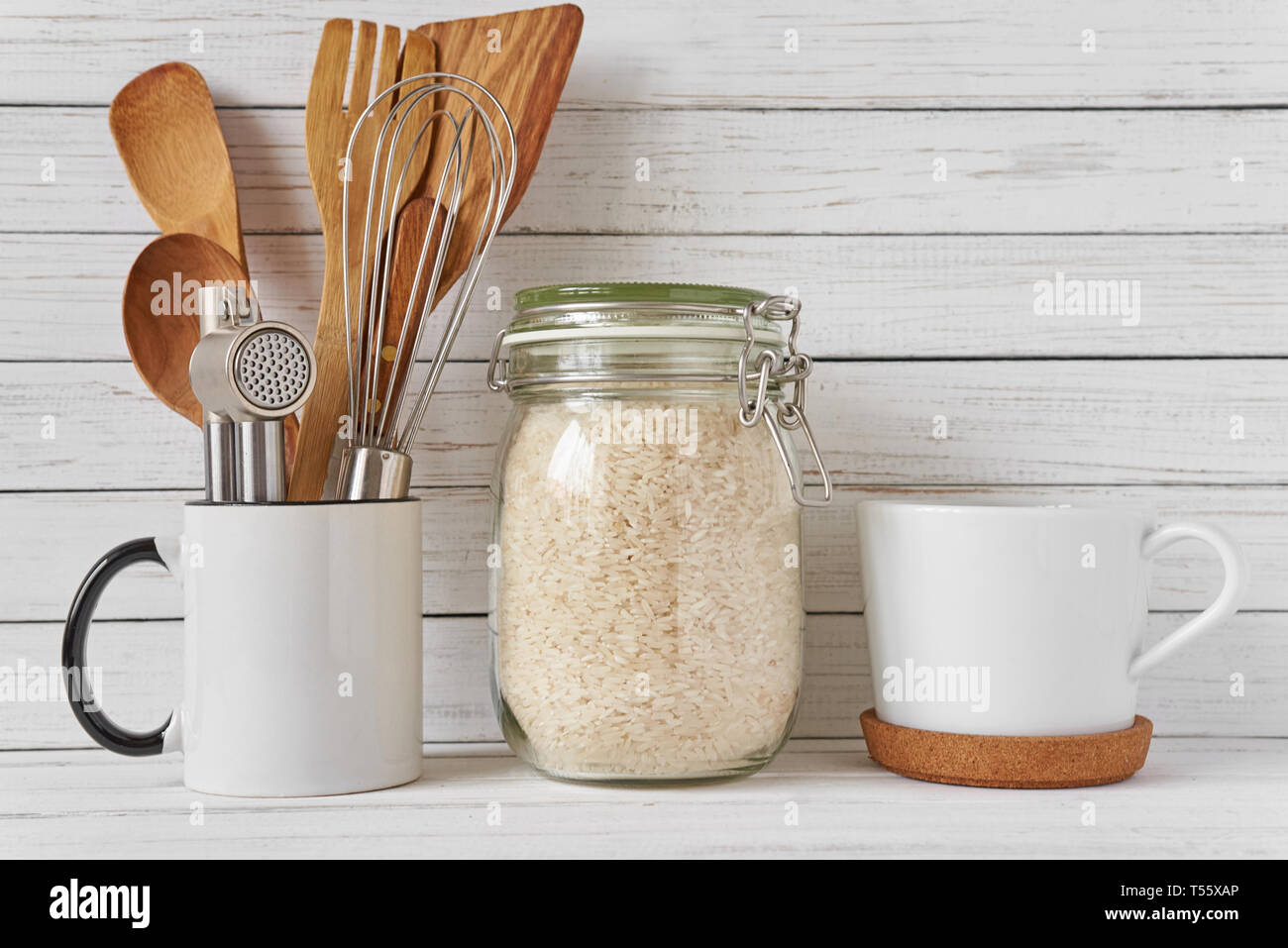 Kitchen tools and glass jar with rice on white table, front view ...
