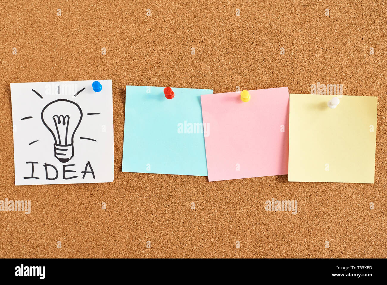 painted light bulb with word idea and colored blank notes on cork board ...