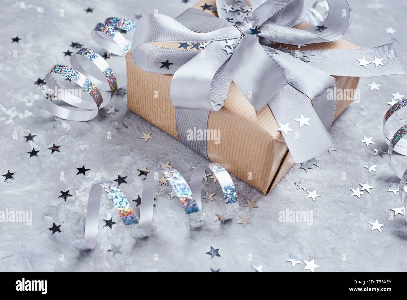 Gift box wrapped in kraft paper with gray bow and confetti in shape ...