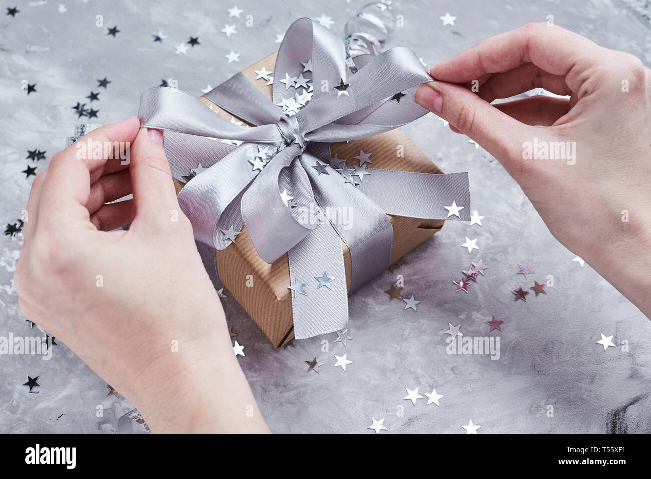 Woman hand tied bow on gift box wrapped in kraft paper Stock Photo - Alamy