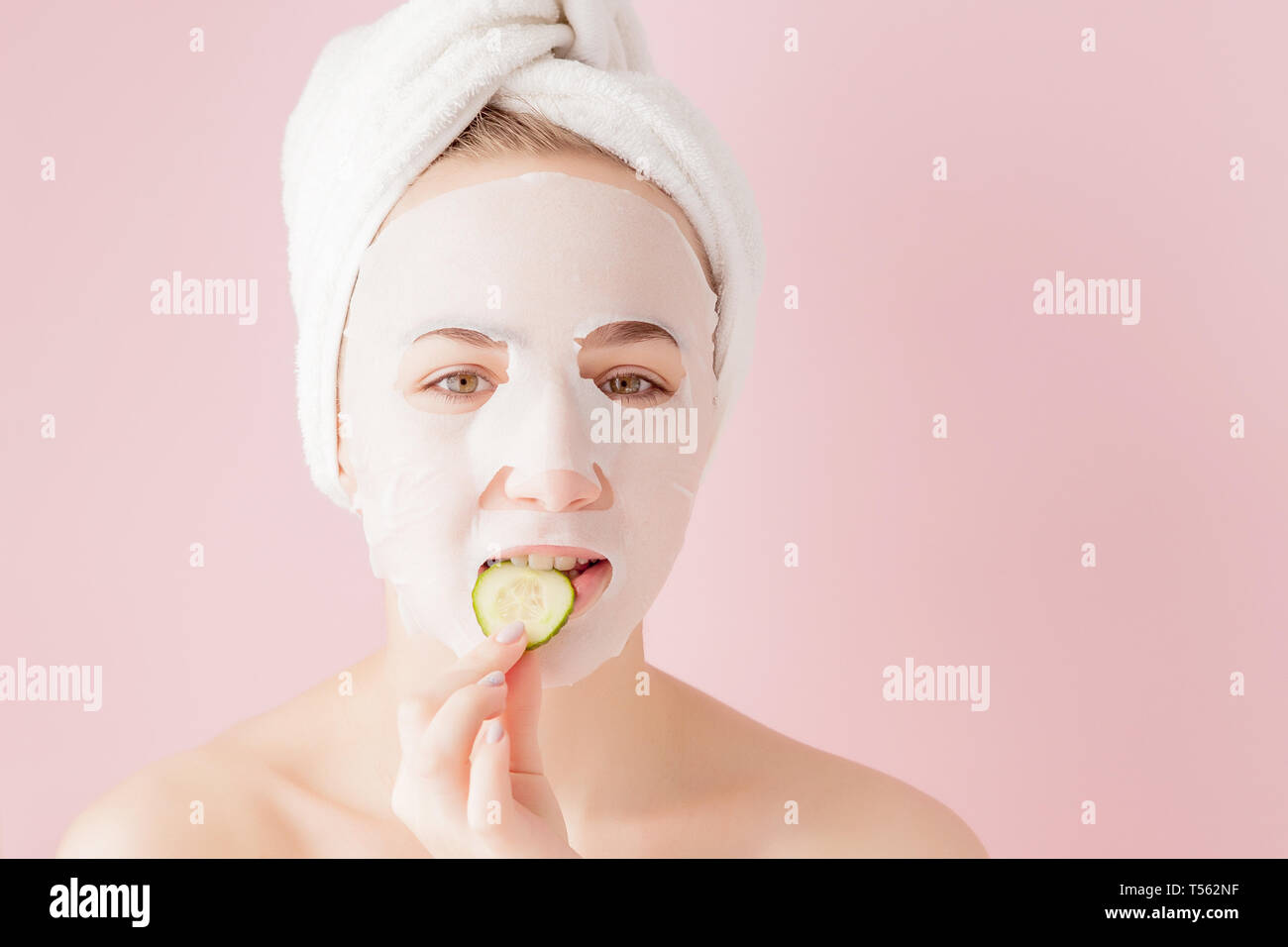 Beautiful young woman is applying a cosmetic tissue mask on a face on a ...