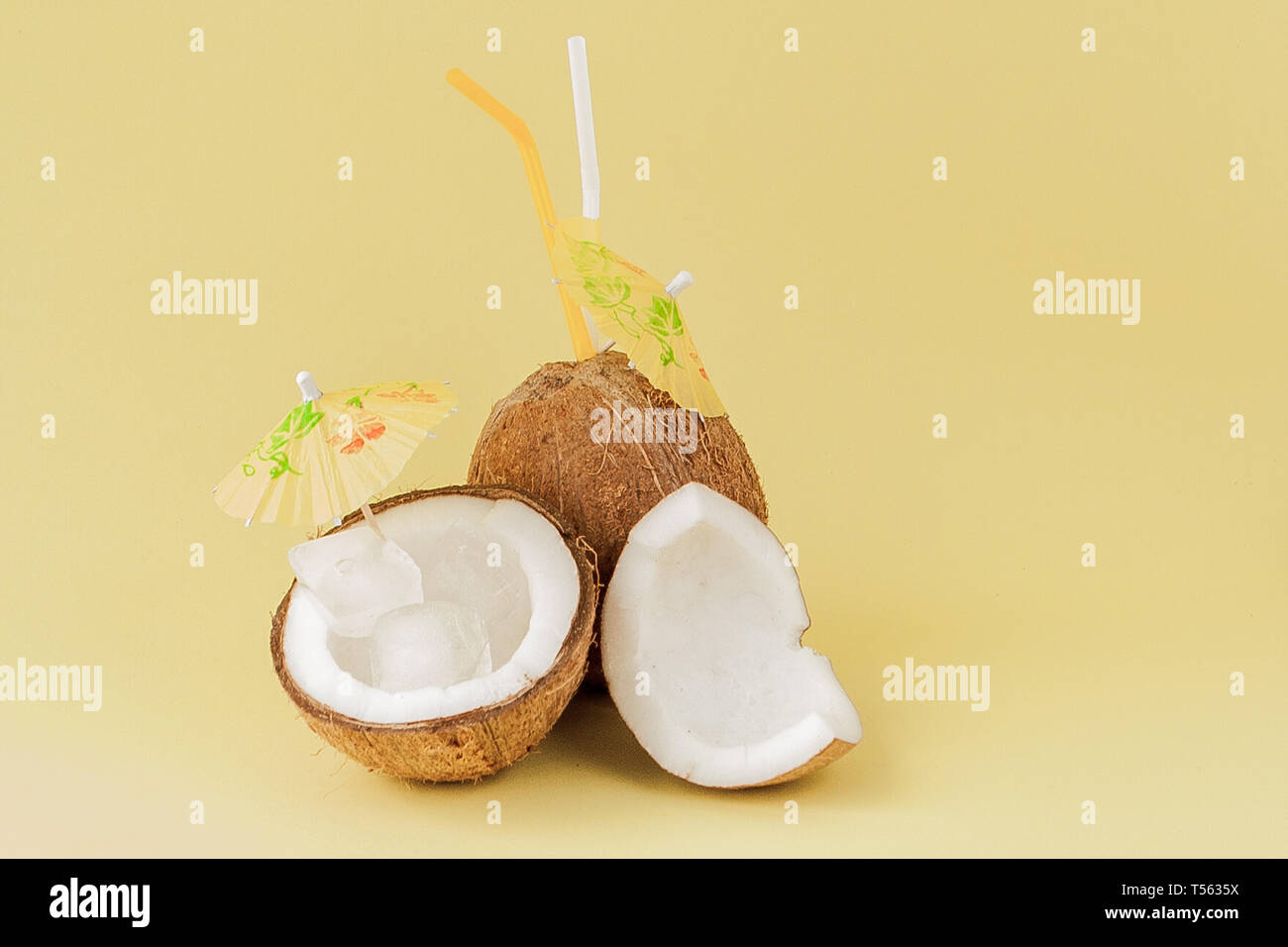 Fresh Coconut cocktail with a straws on yellow background, copy space ...