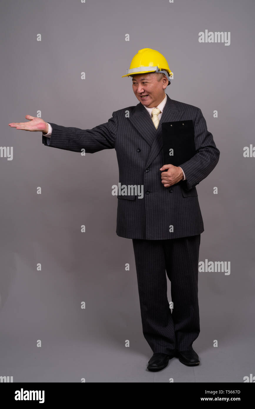 Mature Asian construction businessman against gray background Stock ...