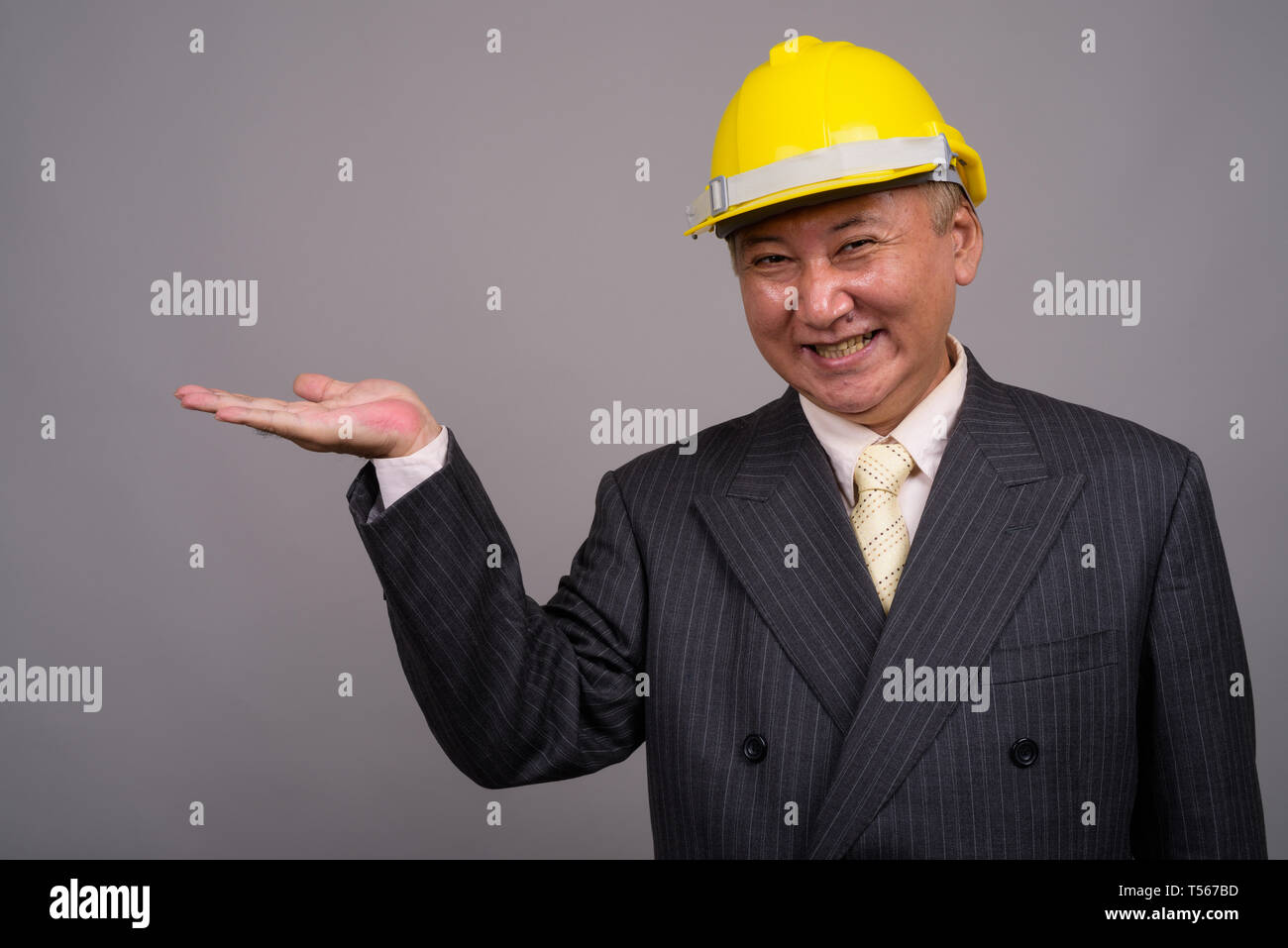 Mature Asian construction businessman against gray background Stock ...