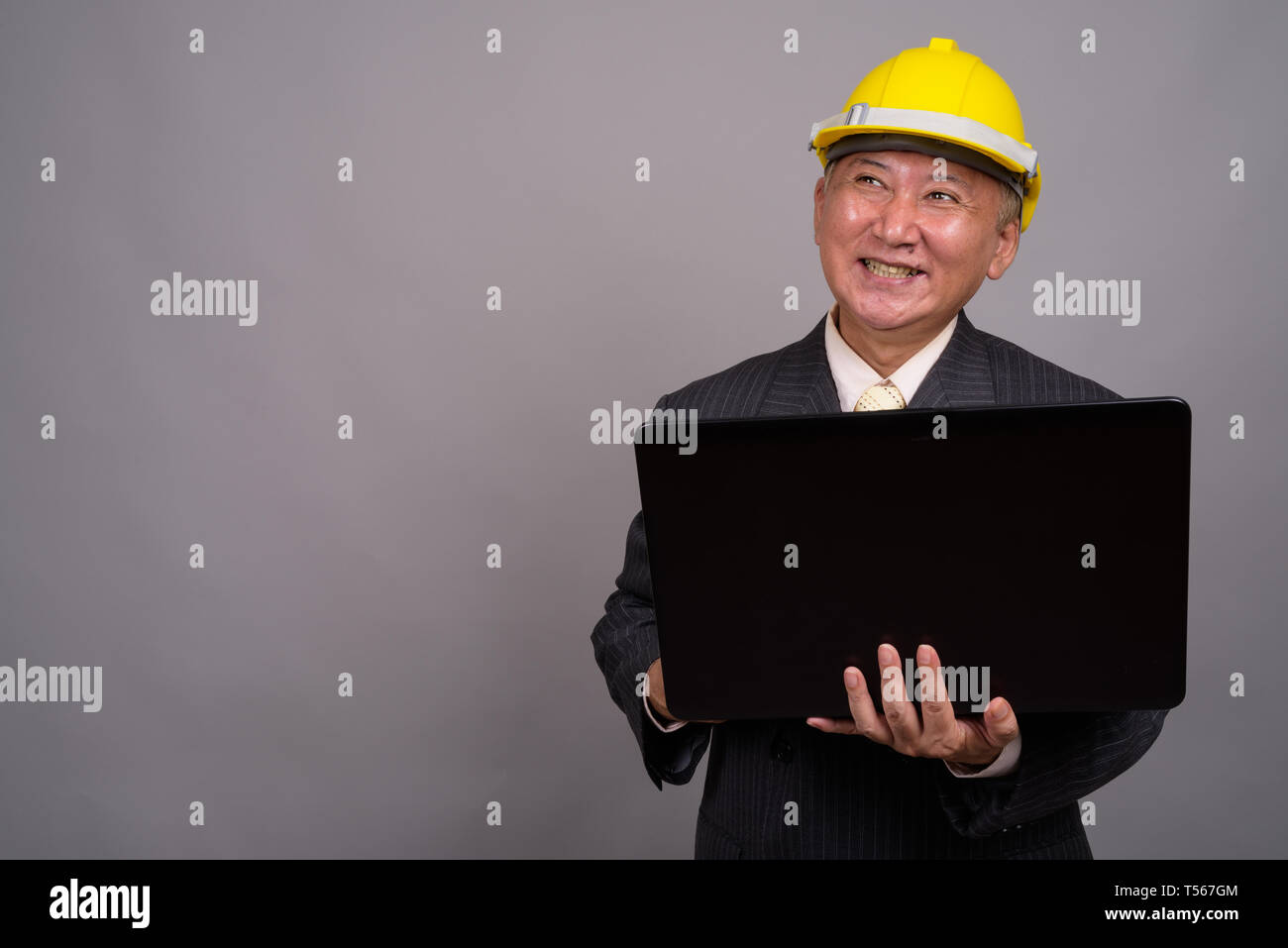 Mature Asian construction businessman against gray background Stock ...