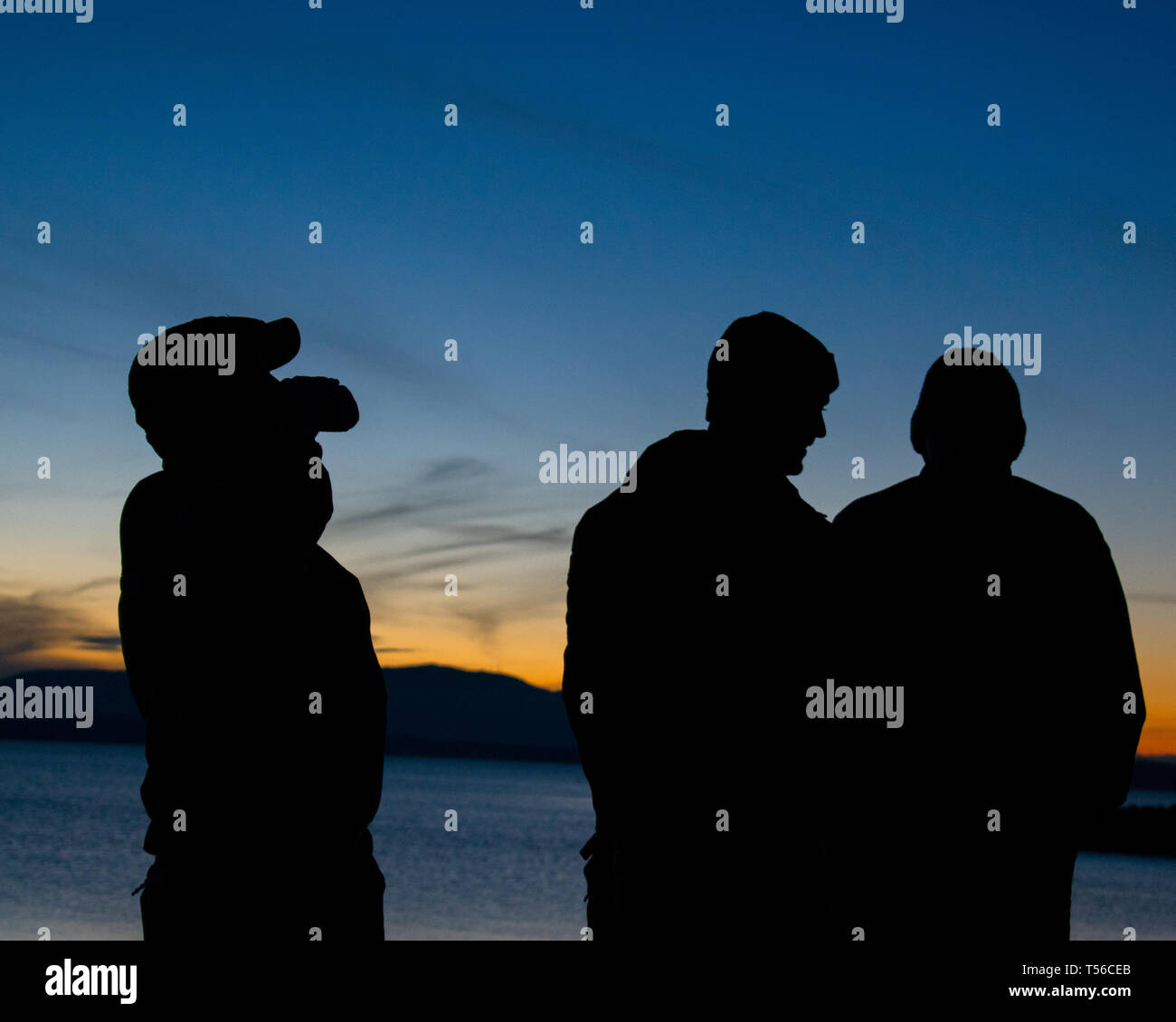 Silhouette of three brothers drinking beer and watching the sunset on ...