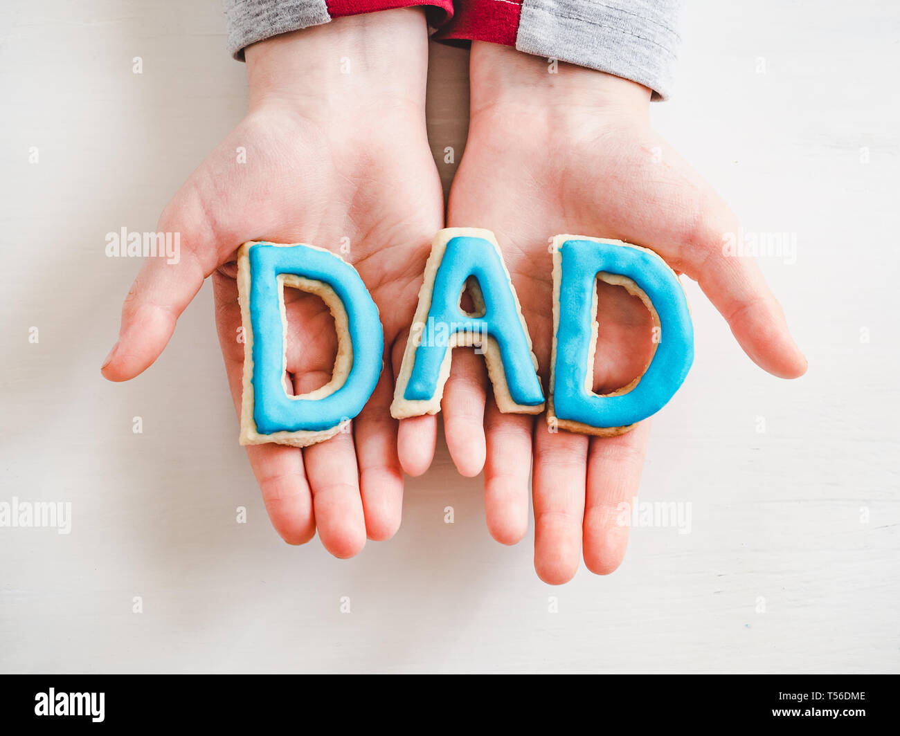 Word DAD made of glazed cookies, lying on the palms of the child and ...